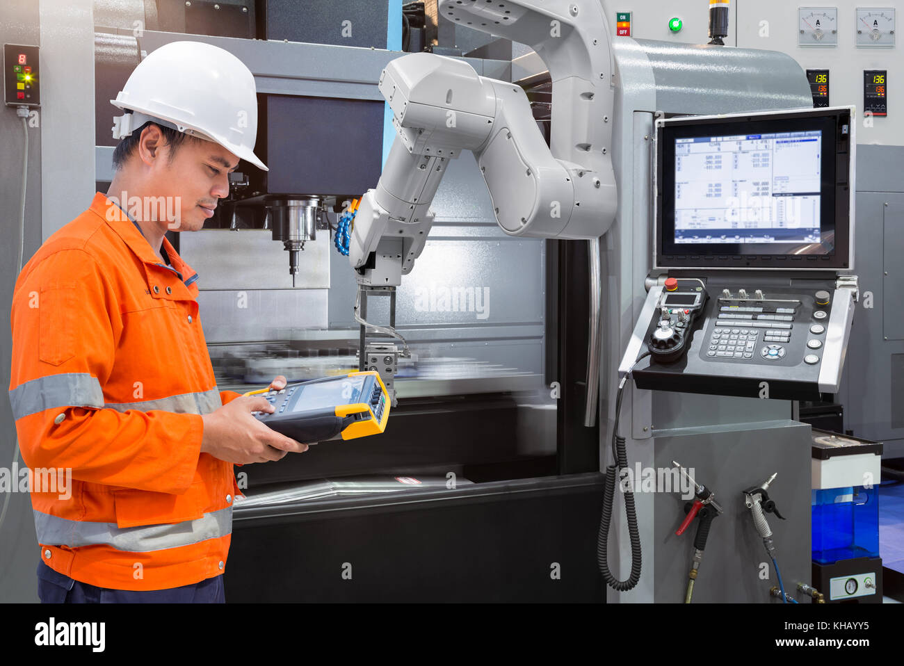 Maintenance engineer programming automatic robotic hand with CNC machine in smart factory ...