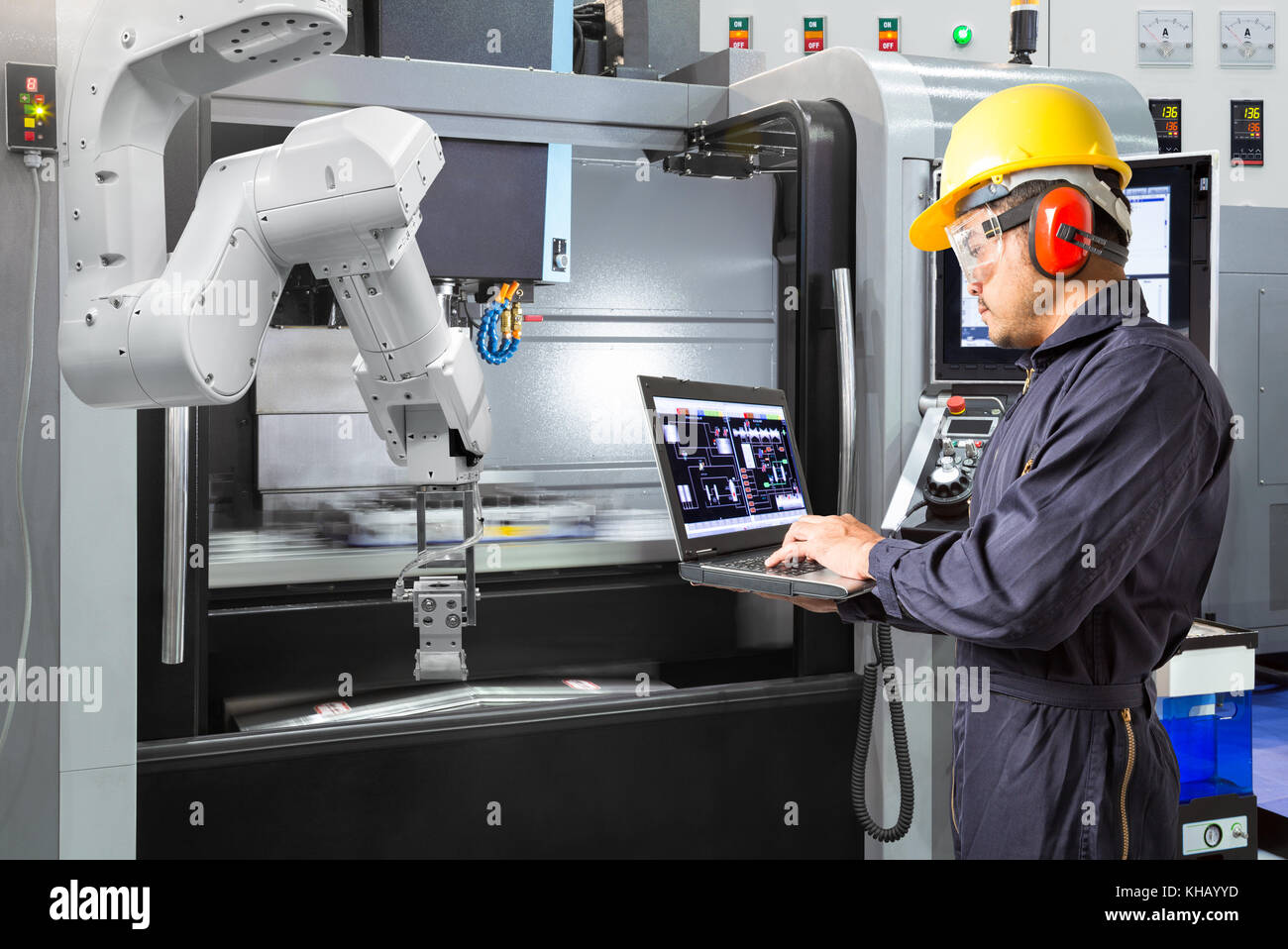 Maintenance engineer using laptop computer control automatic robotic hand with CNC machine in ...
