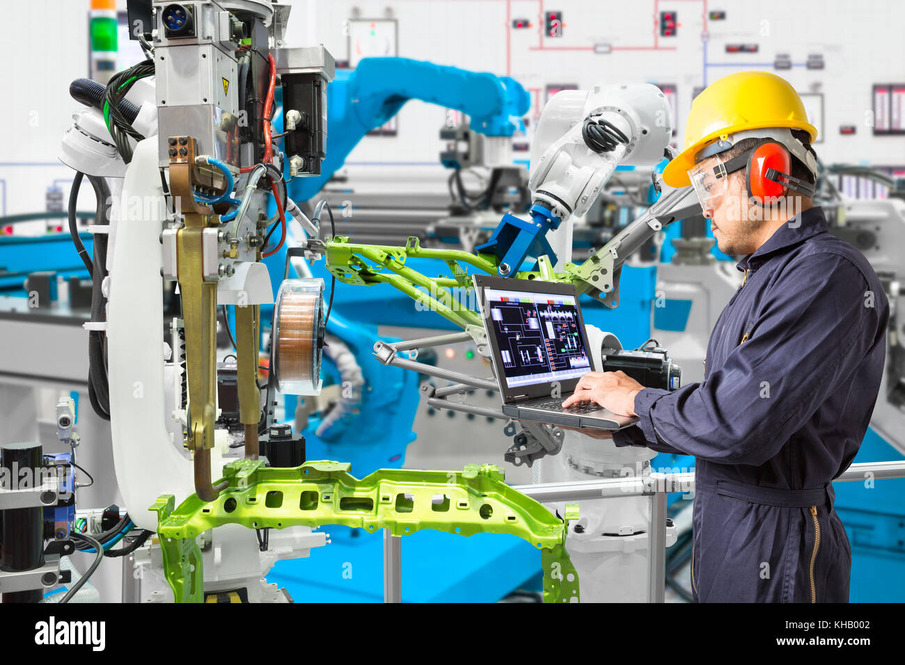 Engineer using laptop computer maintenance automatic robotic welding with robot workpiece in ...