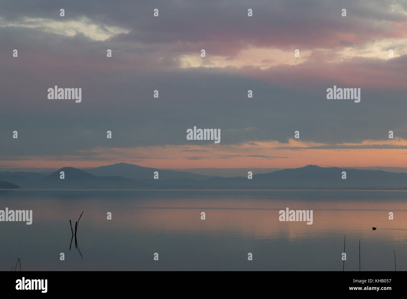 A lake at dusk, with beautiful, warm tones in the sky and water and ...