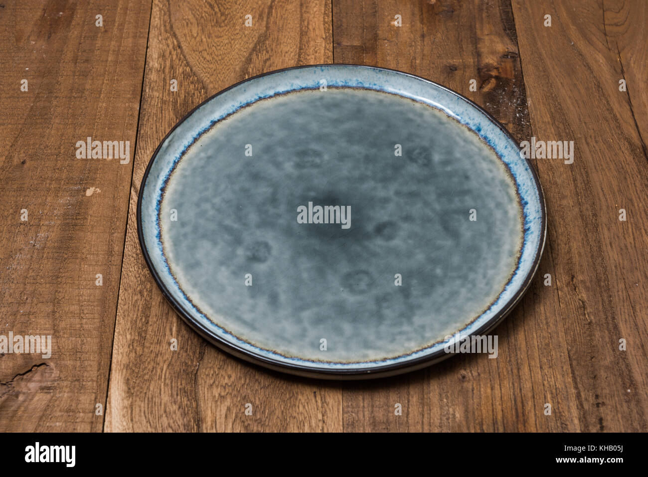 Round Plate on brown wooden table background side view Stock Photo - Alamy