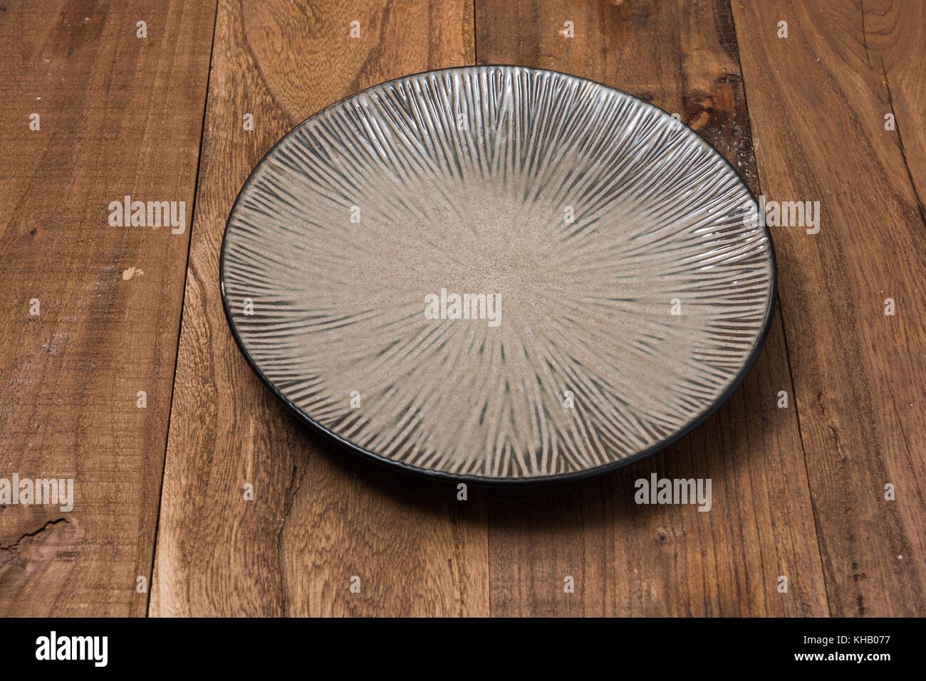 Round Plate on brown wooden table background side view Stock Photo - Alamy