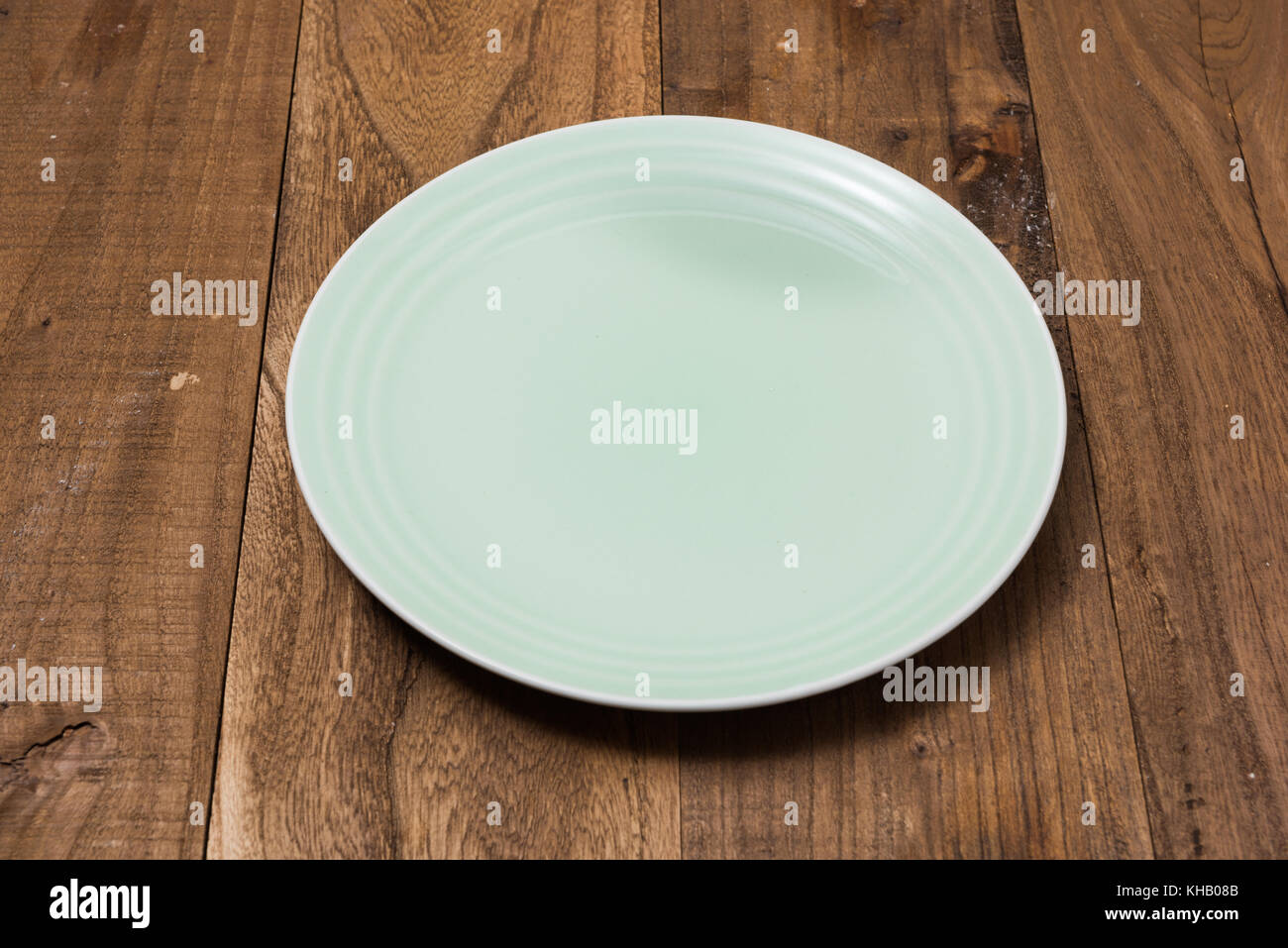 Green Round Plate on brown wooden table background side view Stock ...