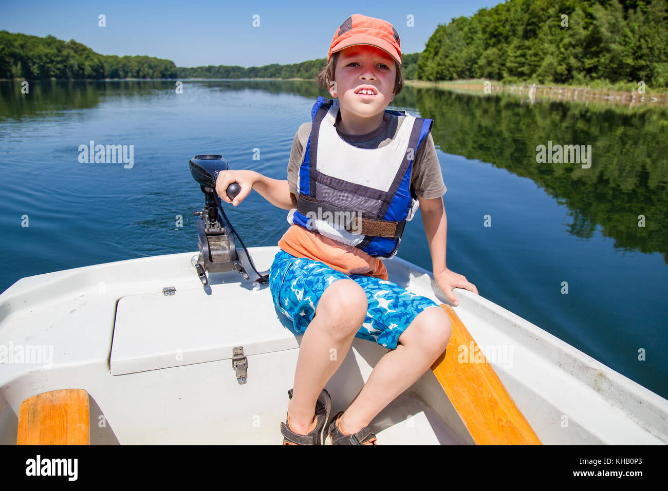 Boy driving a boat with electric outboard motor on a lake in Poland ...
