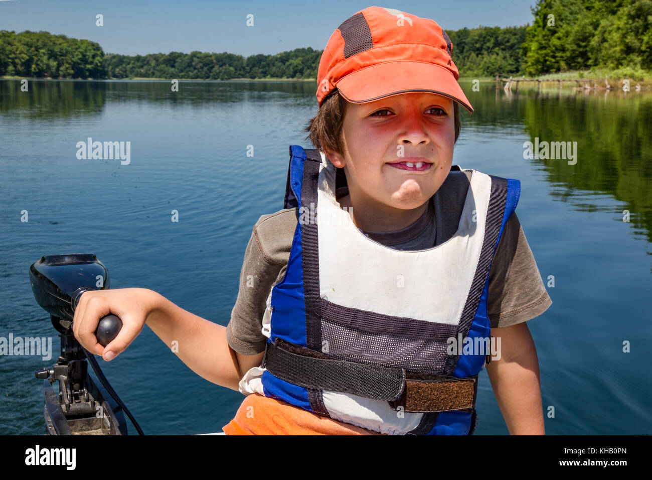 Boy driving a boat with electric outboard motor on a lake in Poland ...