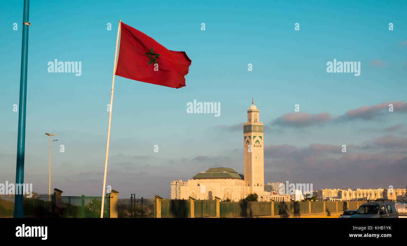 View of the famous Hassan II mosque and a waving moroccan flag against ...