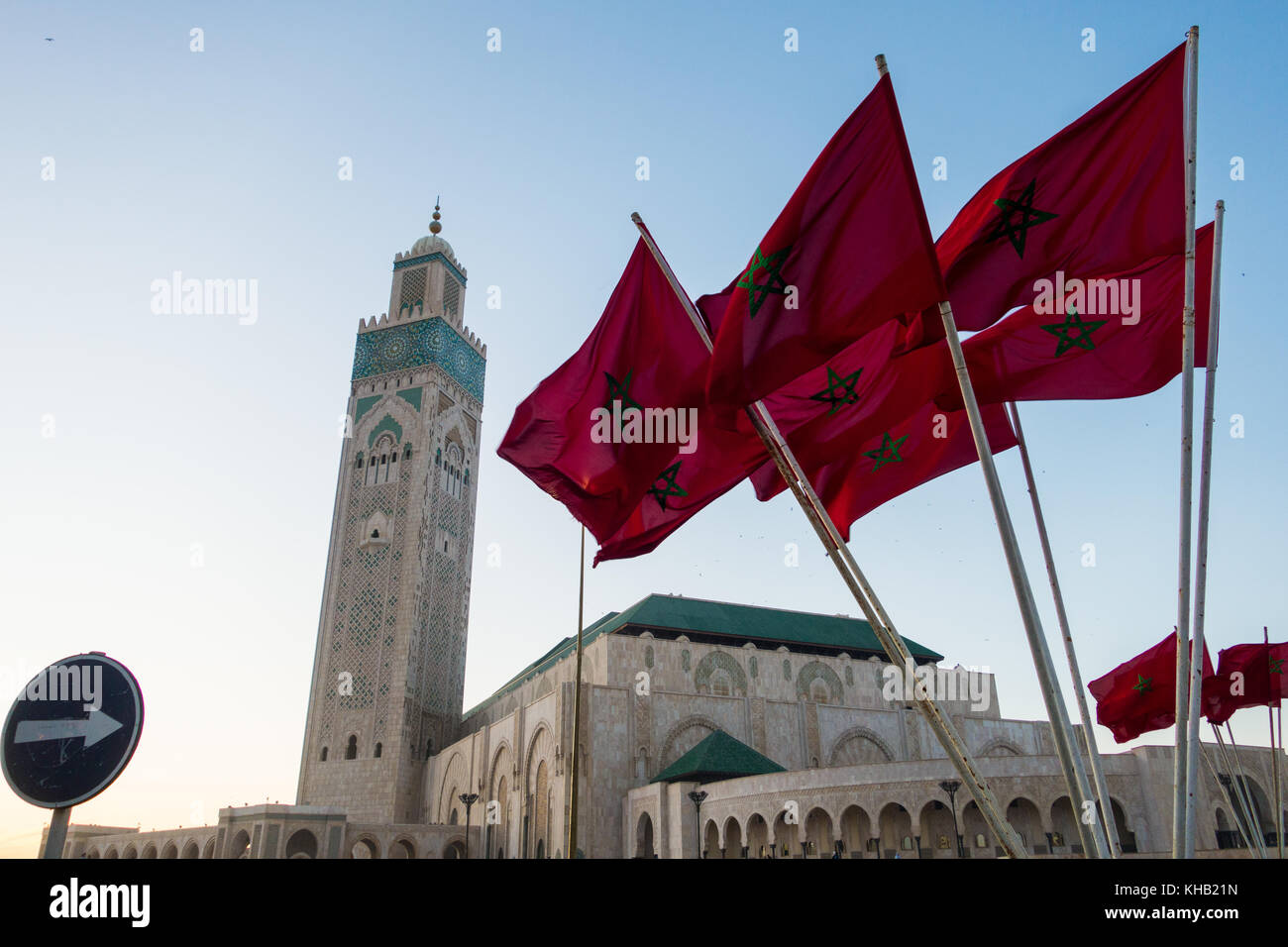 View of Hassan II mosque and a waving moroccan flags against sky ...