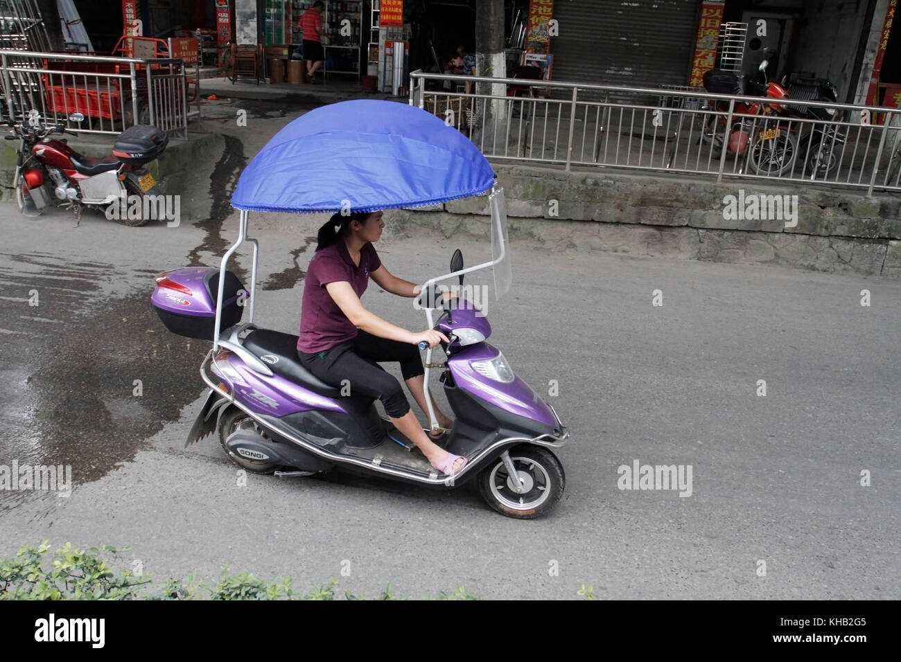 A woman riding a scooter with canvas roof in Guilin, China Stock Photo ...
