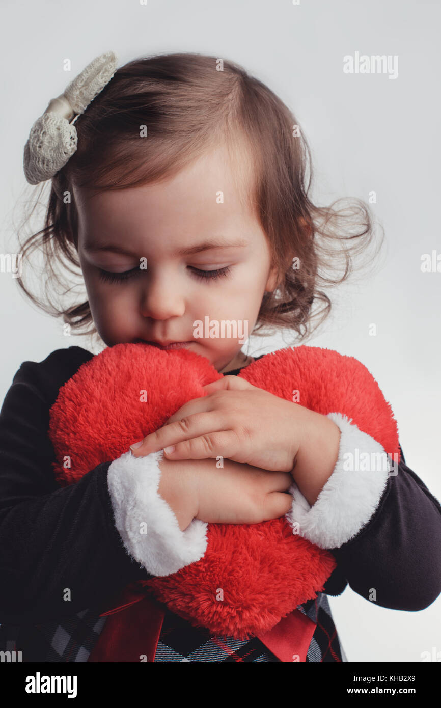 Cute little child girl portrait holding red heart toy on white ...