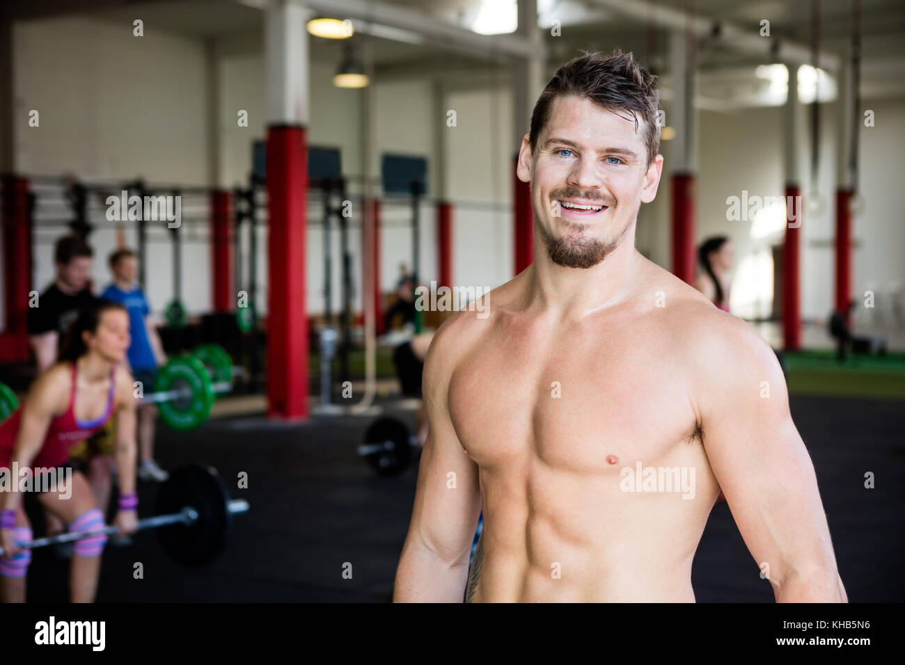 Portrait of happy confident muscular man standing in gym Stock Photo ...