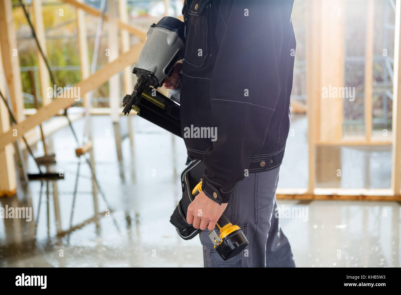 Side view midsection of carpenter with drill machines at construction ...
