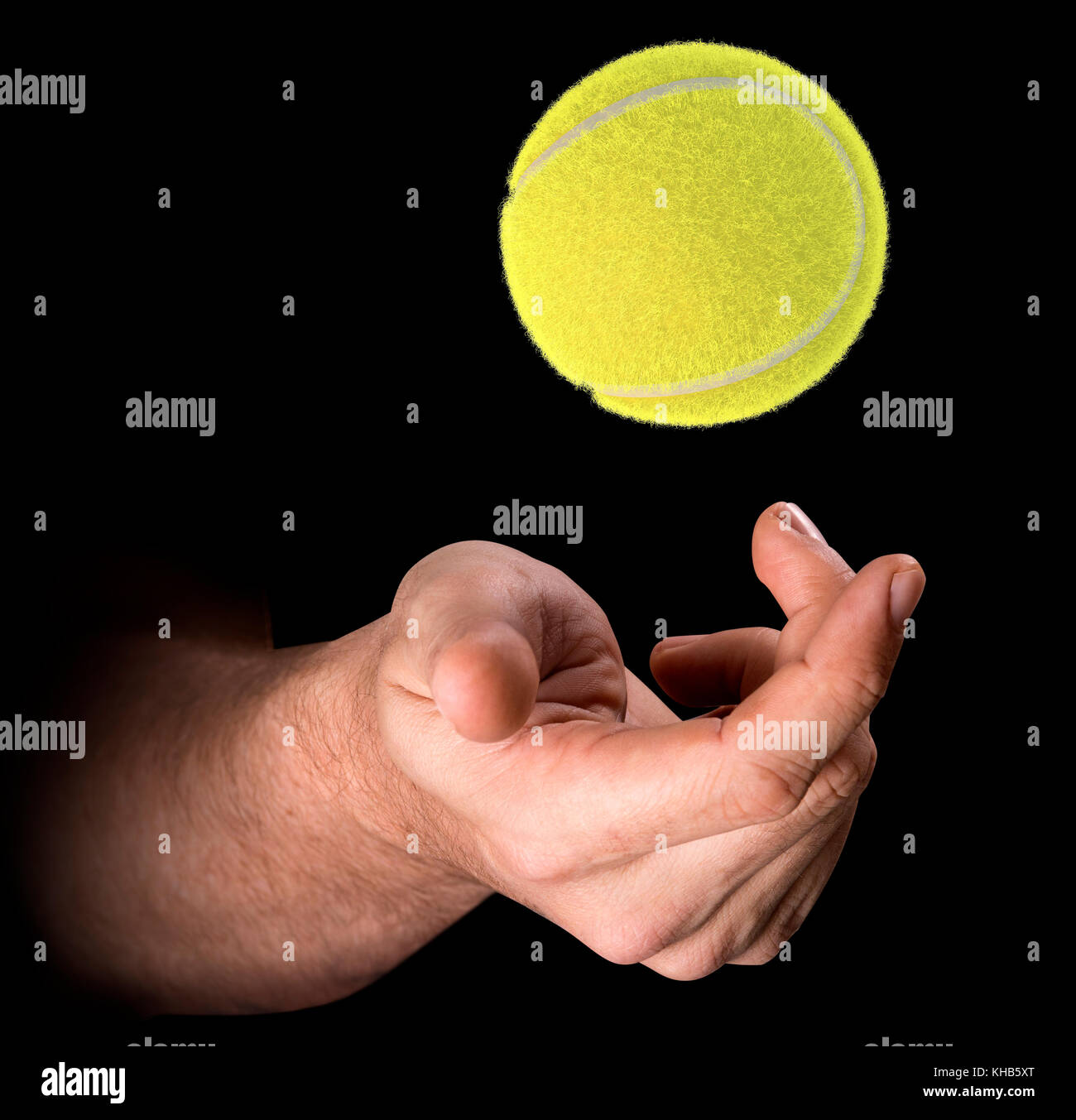 A male hand tossing a tennis ball up in the air on an isolated dark ...