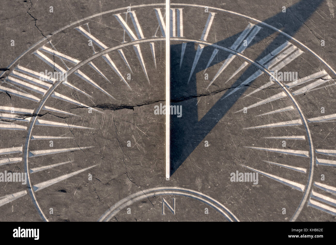 An old stone sundial with etched roman numerals standing an a ...