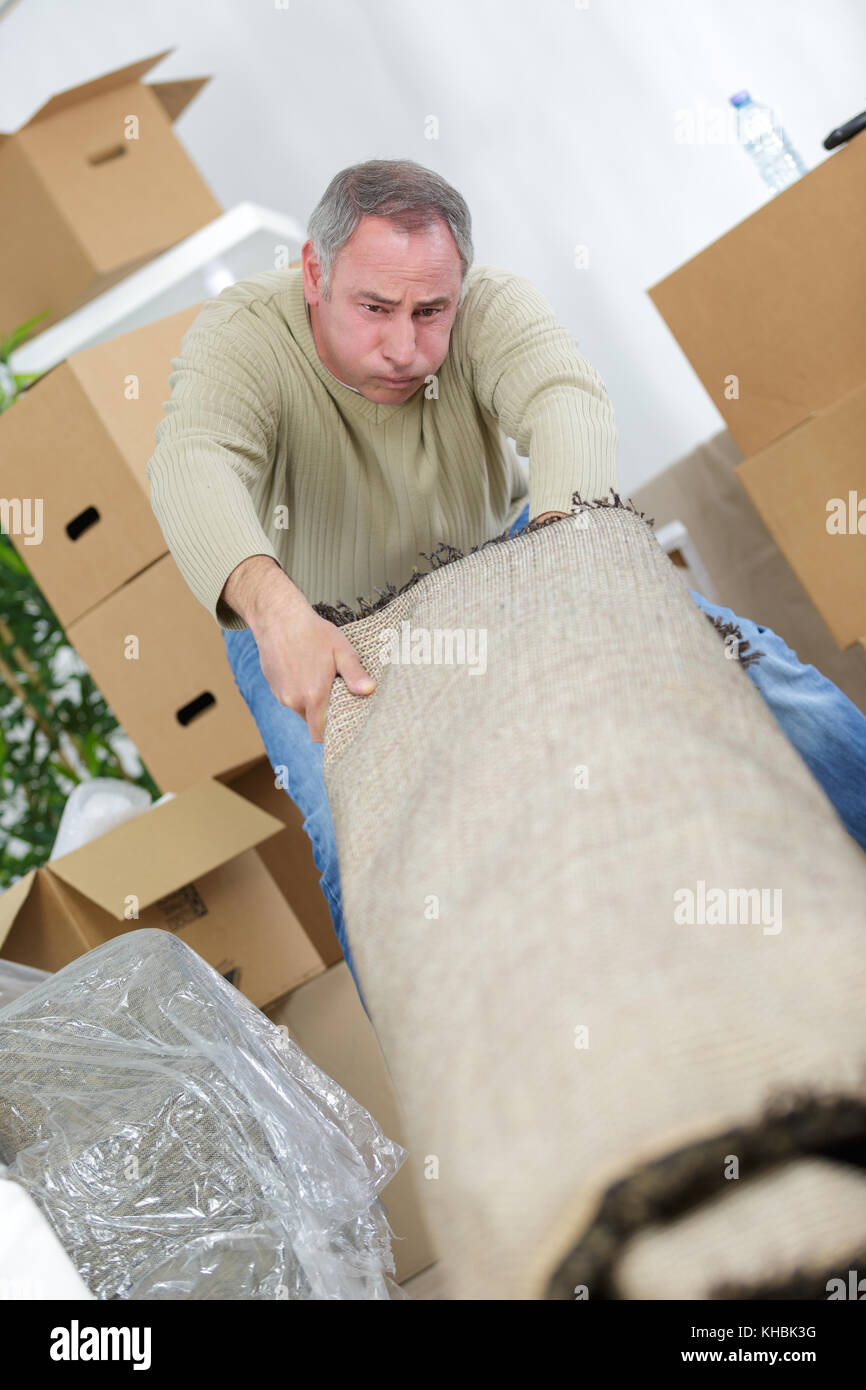man carrying heavy rolled carpet in living room Stock Photo - Alamy