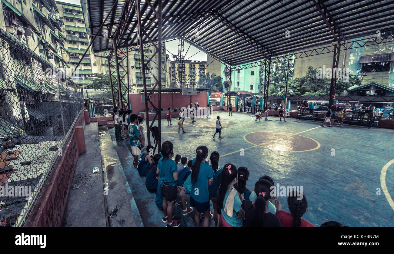 Poor youths playing basketball in slum area. Surrounded by barren ...