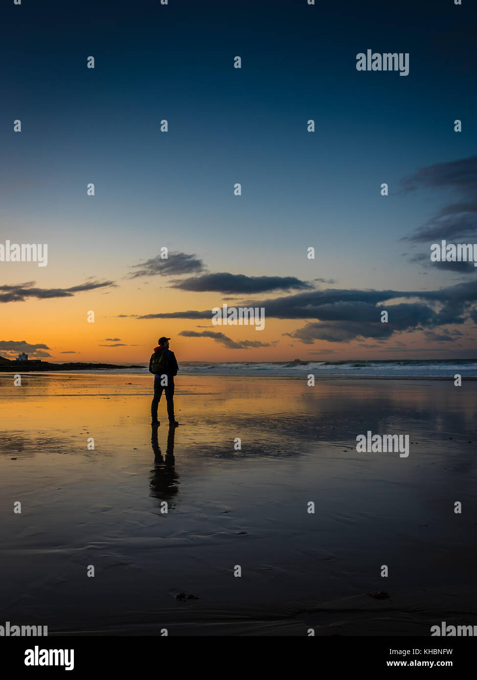 Man standing on beach at sunset Stock Photo - Alamy
