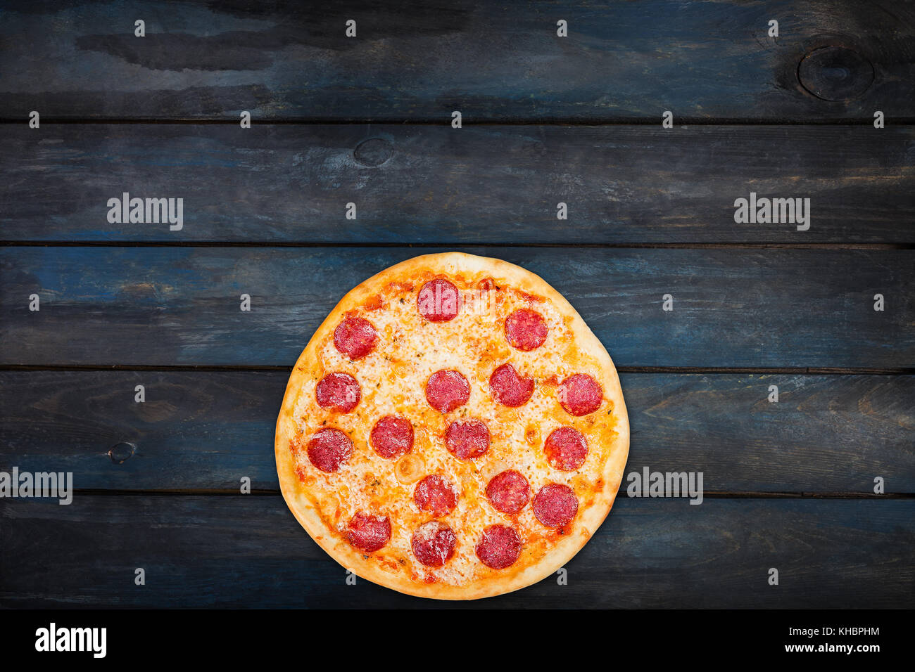 Fresh classic pepperoni pizzai on a dark wooden background. Top view ...