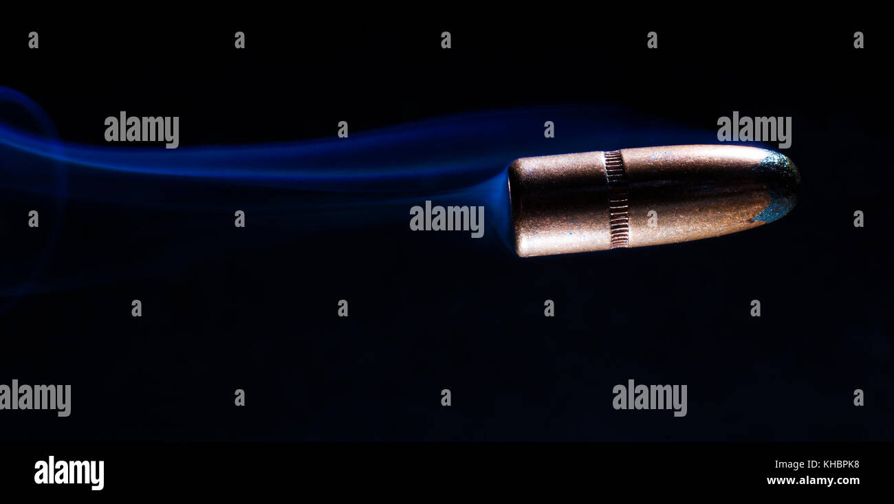 Copper plated rifle bullet on black with smoke behind Stock Photo - Alamy