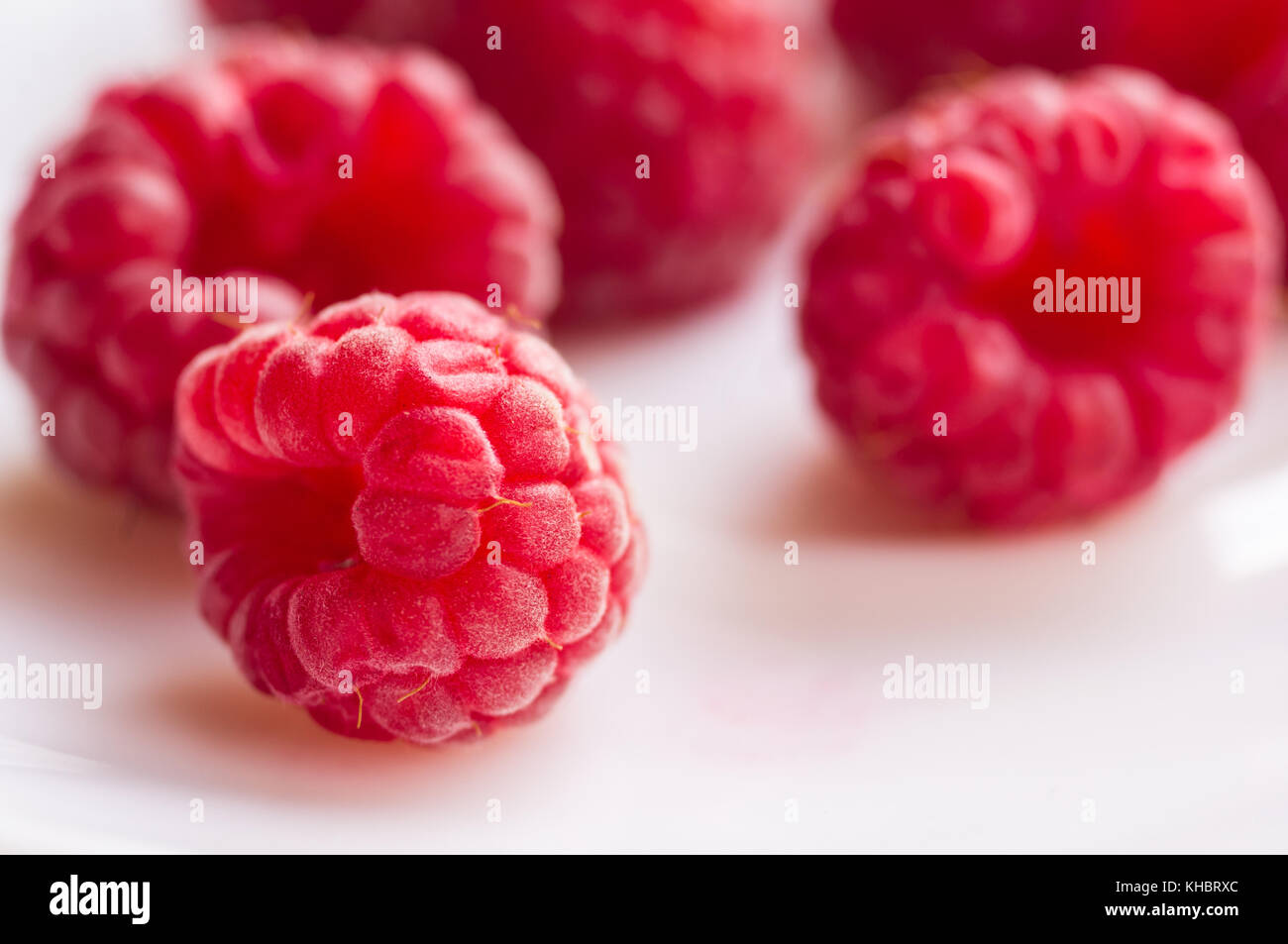 big fresh juicy raspberries on a white saucer close up, selected focus ...