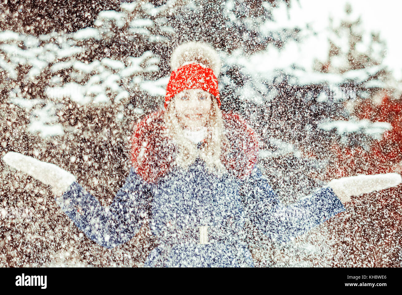 Woman wearing a red jacket throwing snow in the air in winter holidays ...