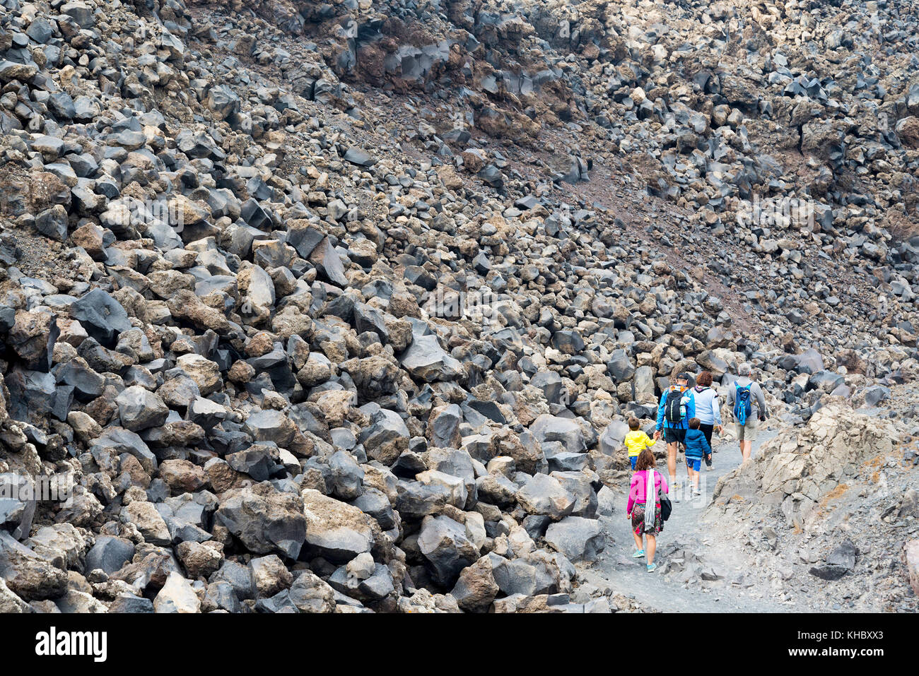 People walk along the volcanic rocks from the rocks on the island of ...