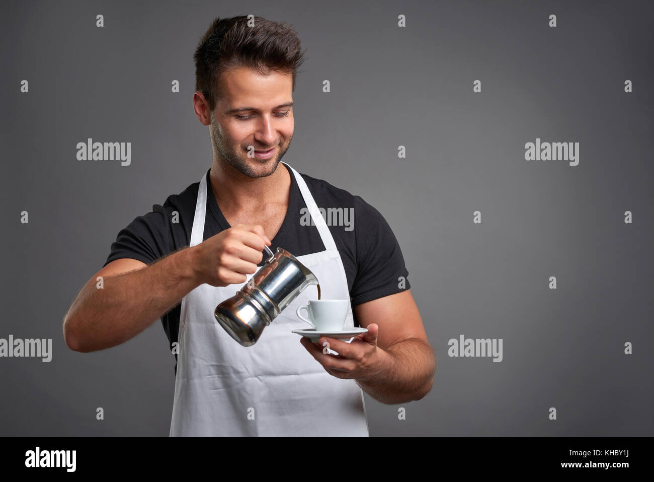 A young barista man smiling and pouring coffee from a percolator to a ...