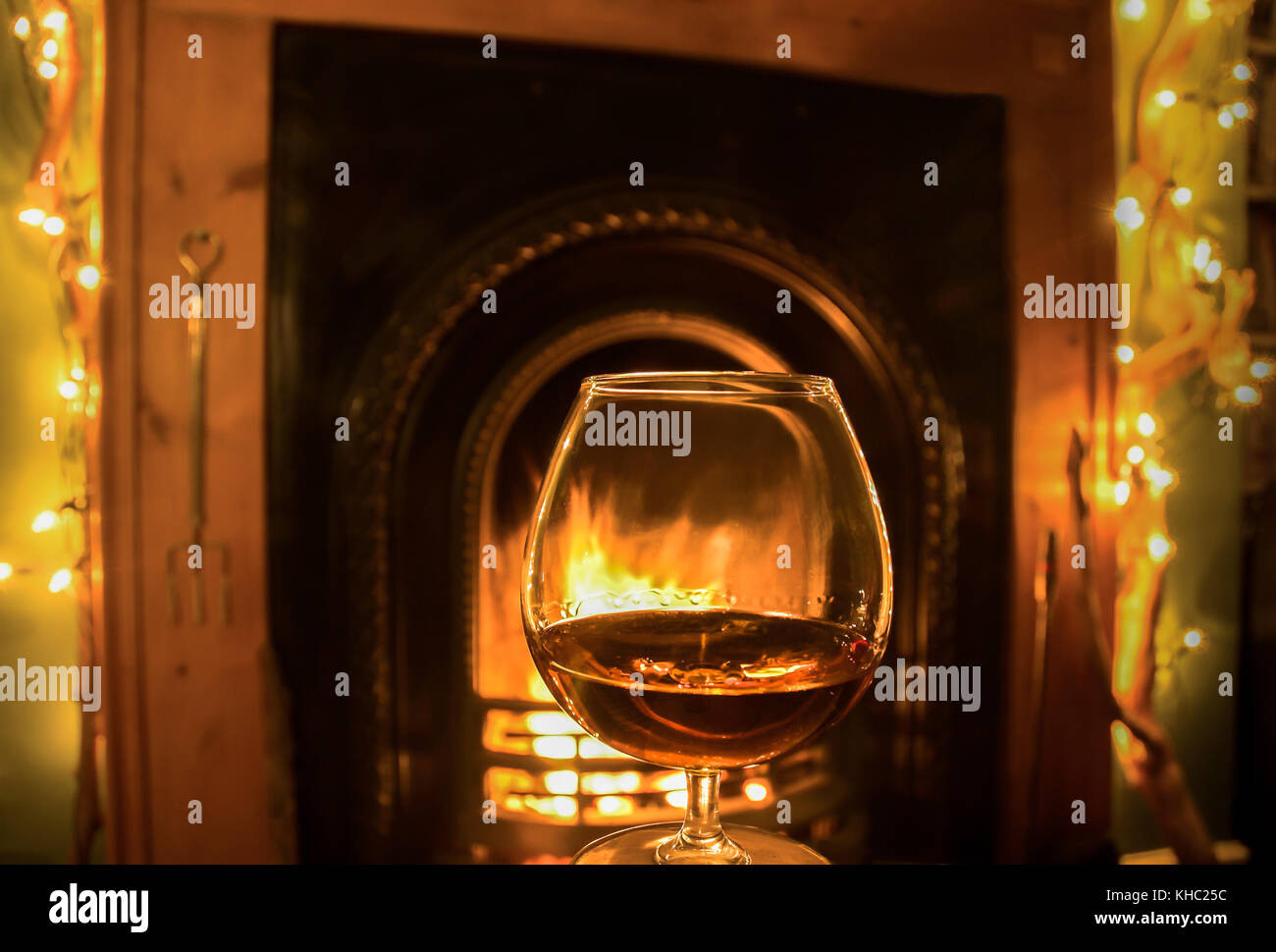 A glas of brandy warming by a cosy fireside in winter Stock Photo - Alamy