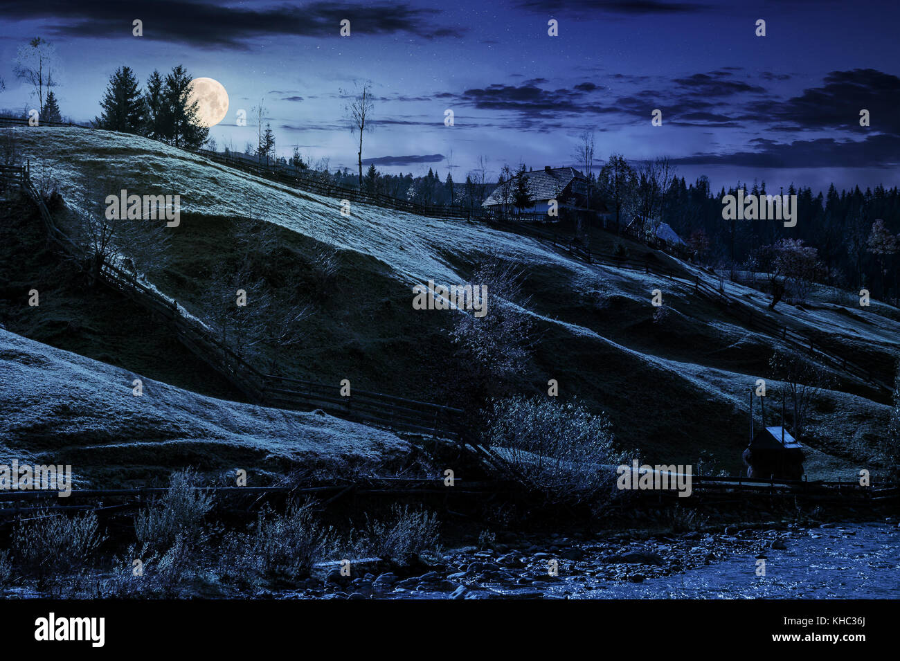 grassy rural hillside near the village at night in full moon light ...