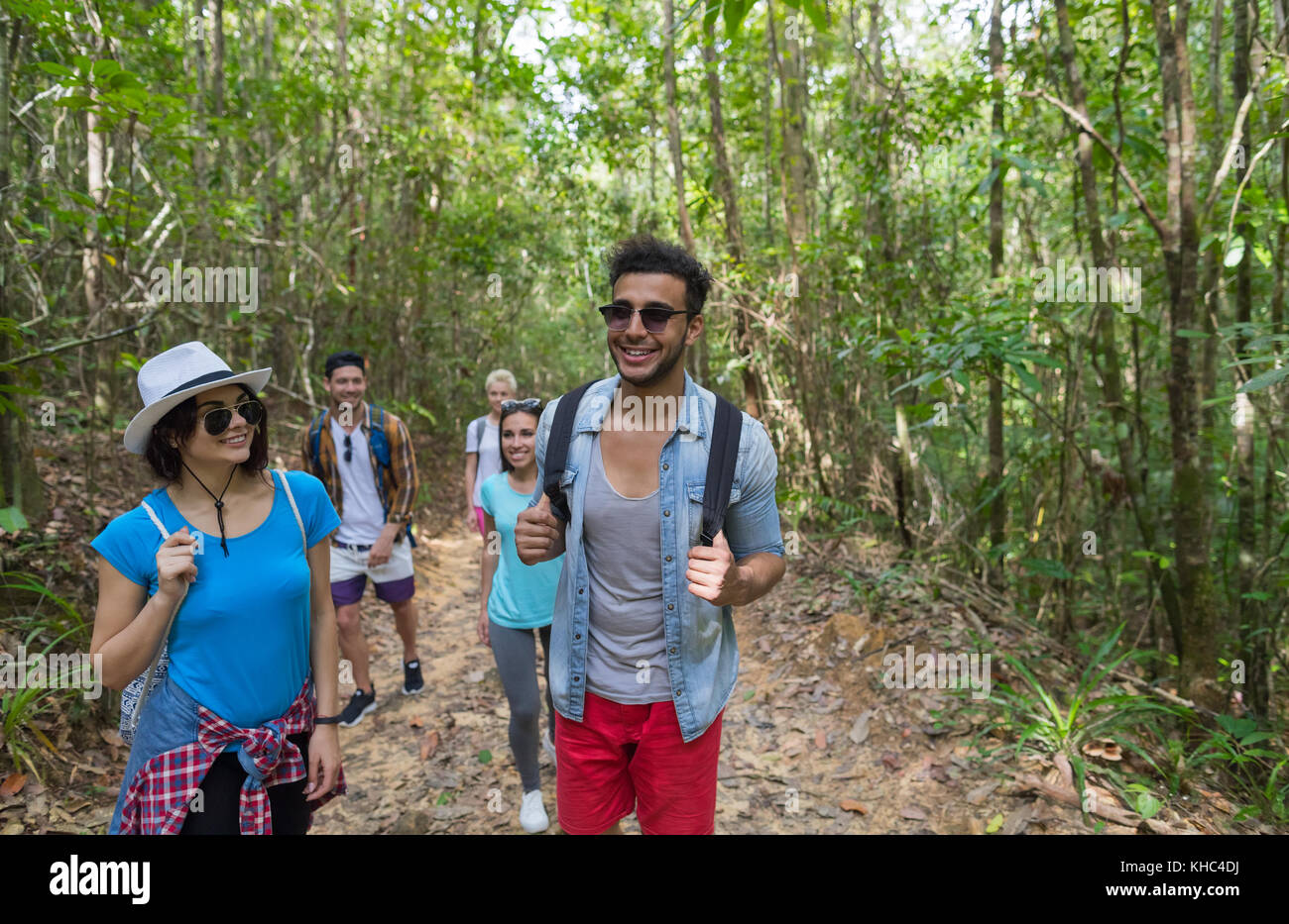 People Group With Backpacks Trekking On Forest Path, Young Men And ...
