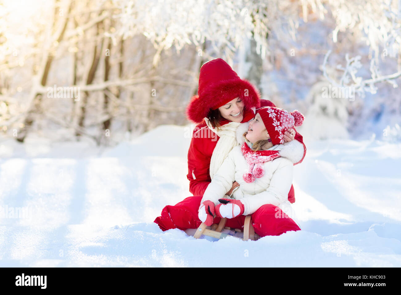 Mother and baby on sleigh ride. Child and mom sledding. Toddler kid ...