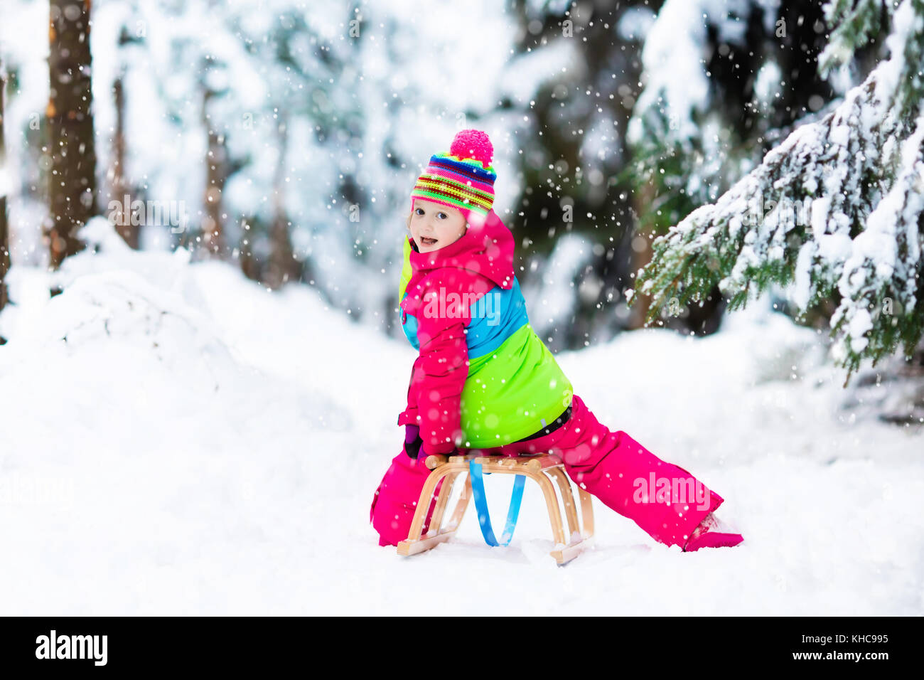 Little girl enjoying a sleigh ride. Child sledding. Toddler kid riding ...