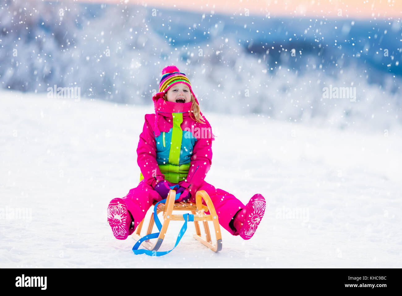 Little girl enjoying a sleigh ride. Child sledding. Toddler kid riding ...