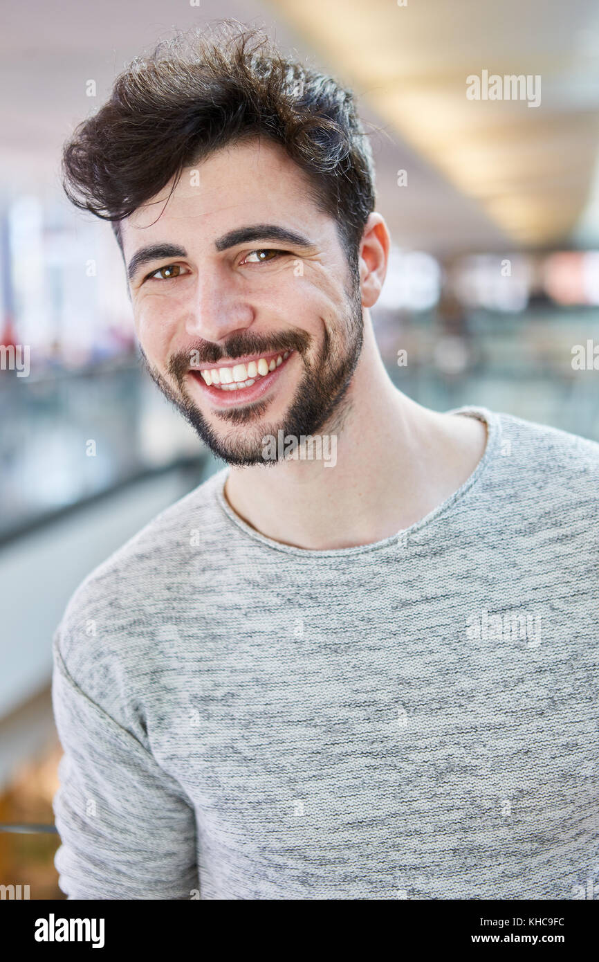 Happy young man with beard and gray shirt in shopping mall Stock Photo ...