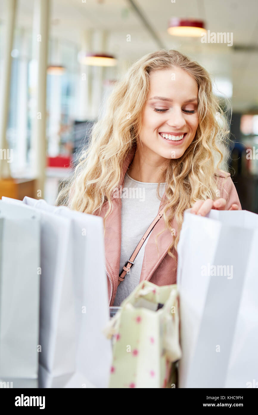 Young blonde woman as a customer looks in her shopping bags while ...