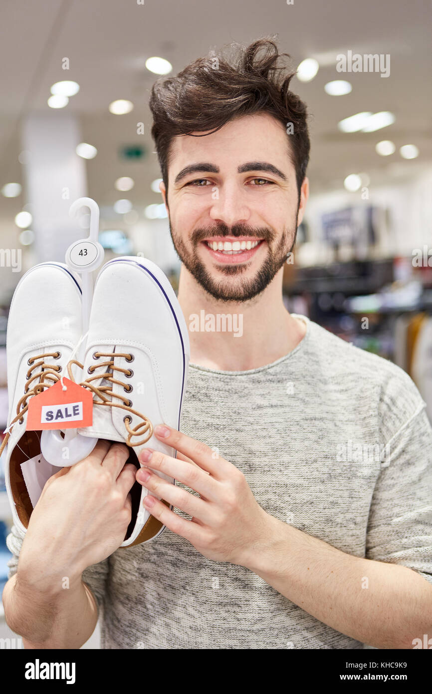 Happy young man is happy about shoes in fashion shop Stock Photo - Alamy