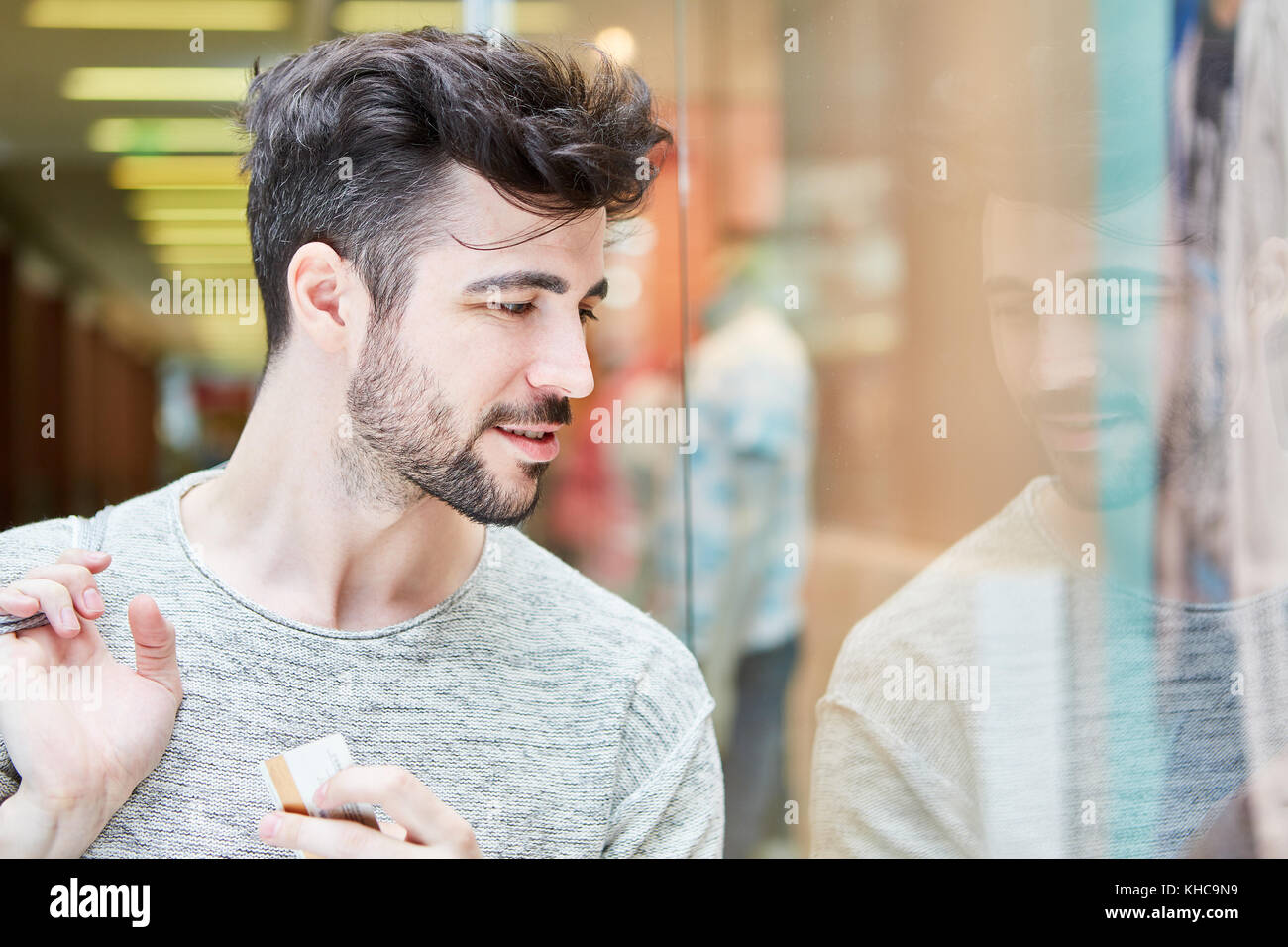 Young man in shopping mall while shopping in front of a shop window ...