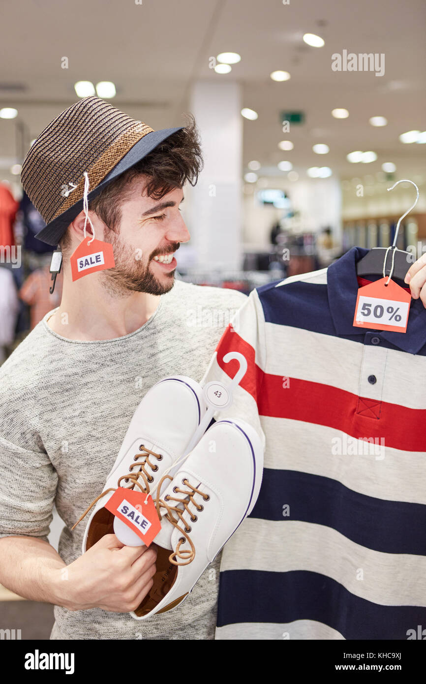 Young man as a customer shopping for clothes with 50% off discount ...