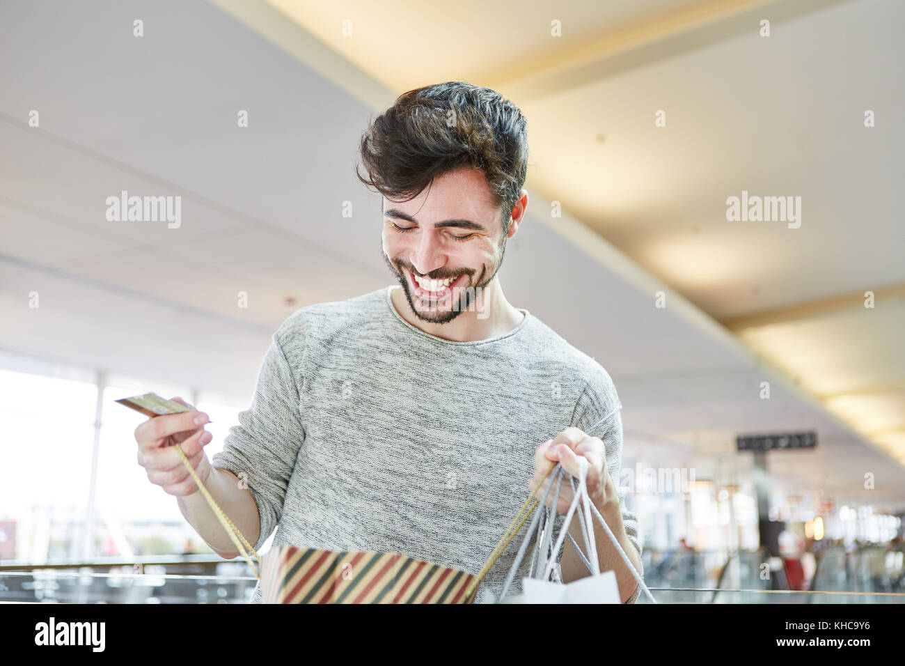 Young man as a buyer is happy about shopping while shopping at retail ...