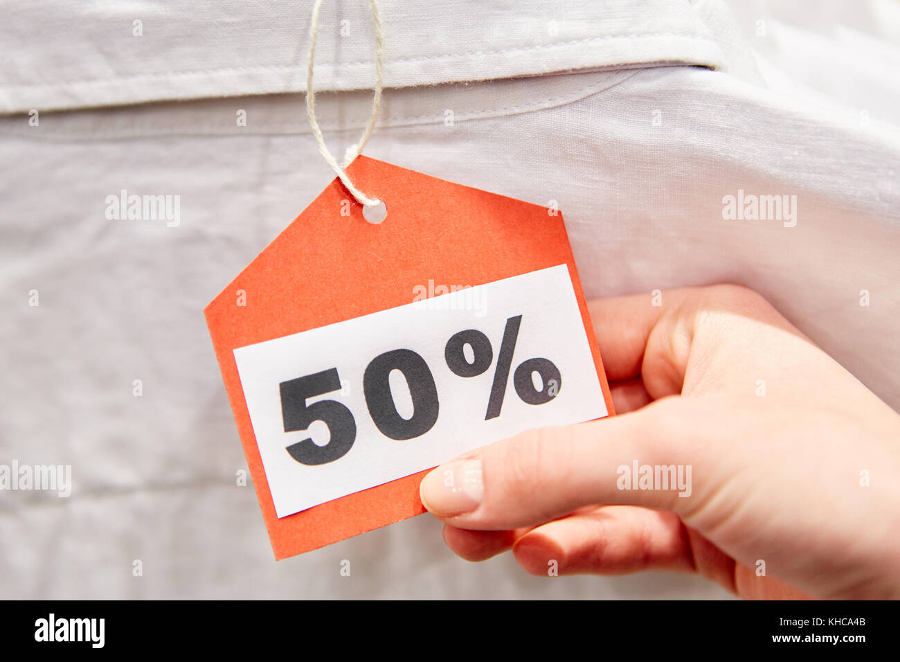 Hand holding price tag with 50% off discount in fashion retail store ...