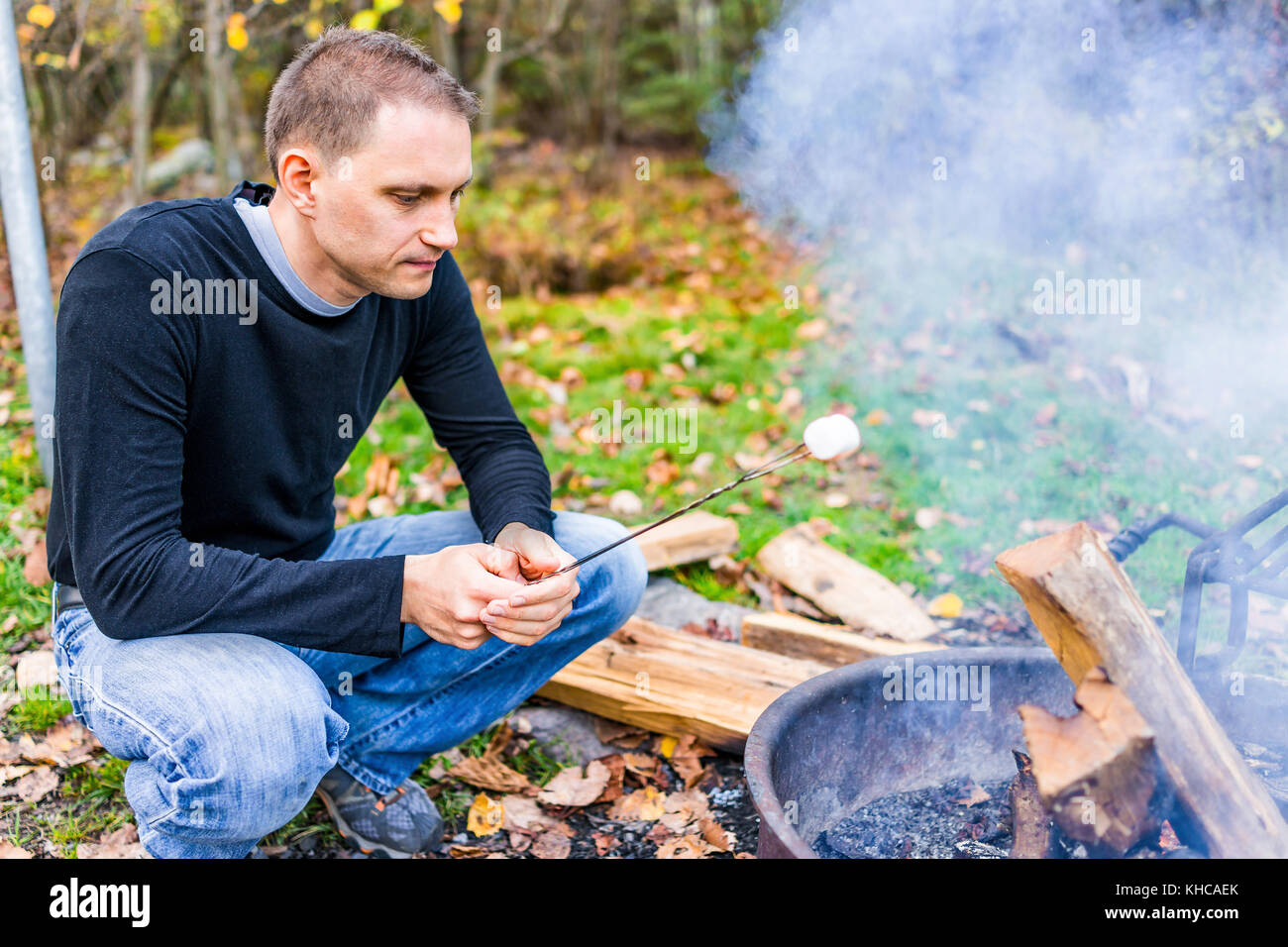 Closeup of young man roasting one white marshmallow caramelizing on ...