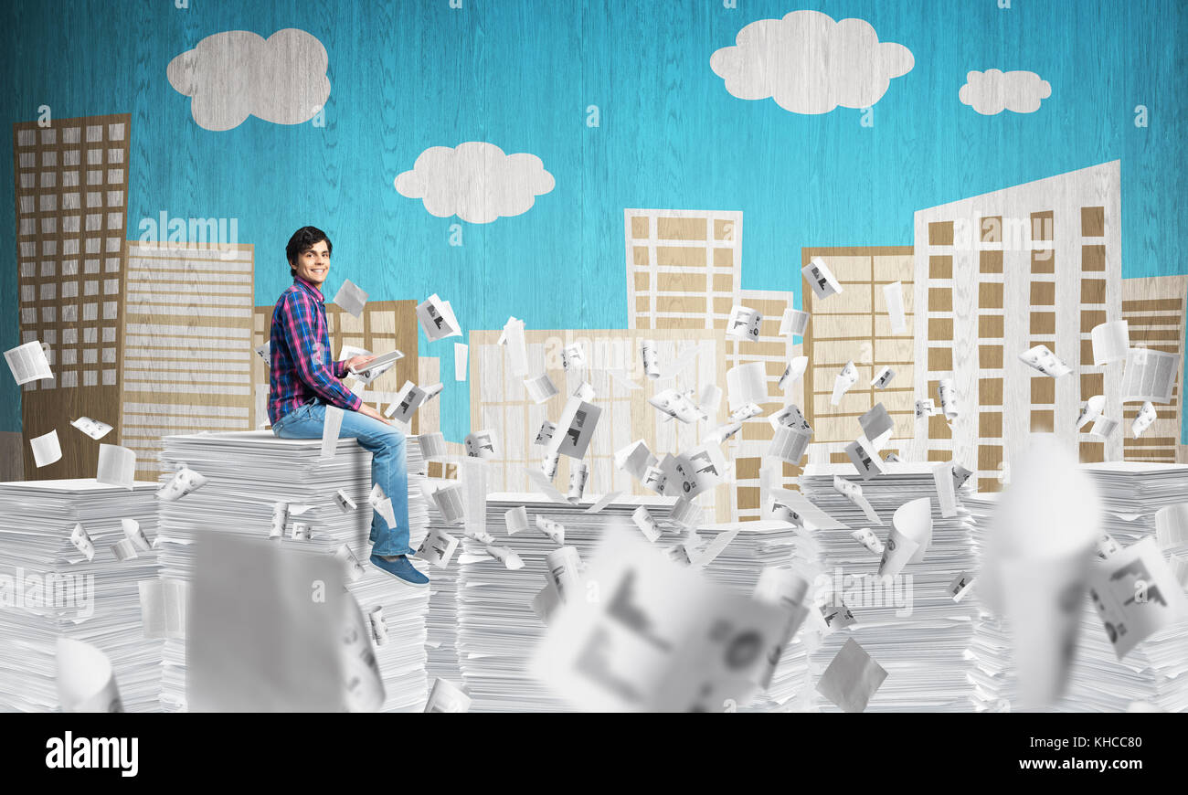 Young man sitting on pile of paper documents Stock Photo - Alamy