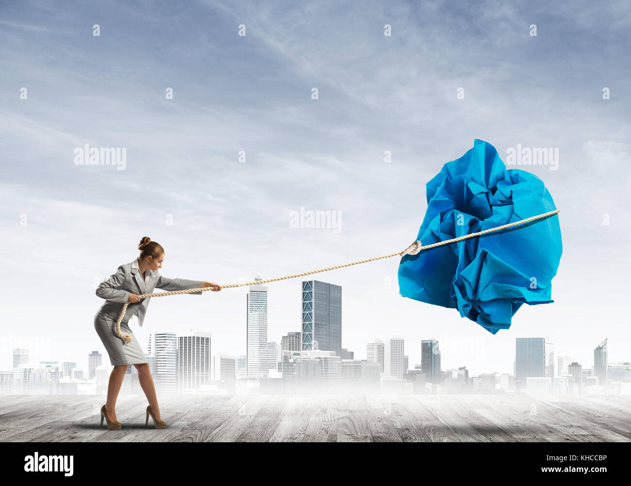 Woman pulling with effort big crumpled ball of paper as creativity sign ...