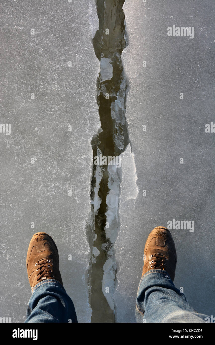 Cracked ice and man leg. Danger background Stock Photo - Alamy