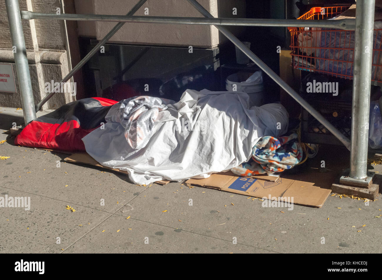 A homeless individual sleeps in front of a vacant storefront in New ...