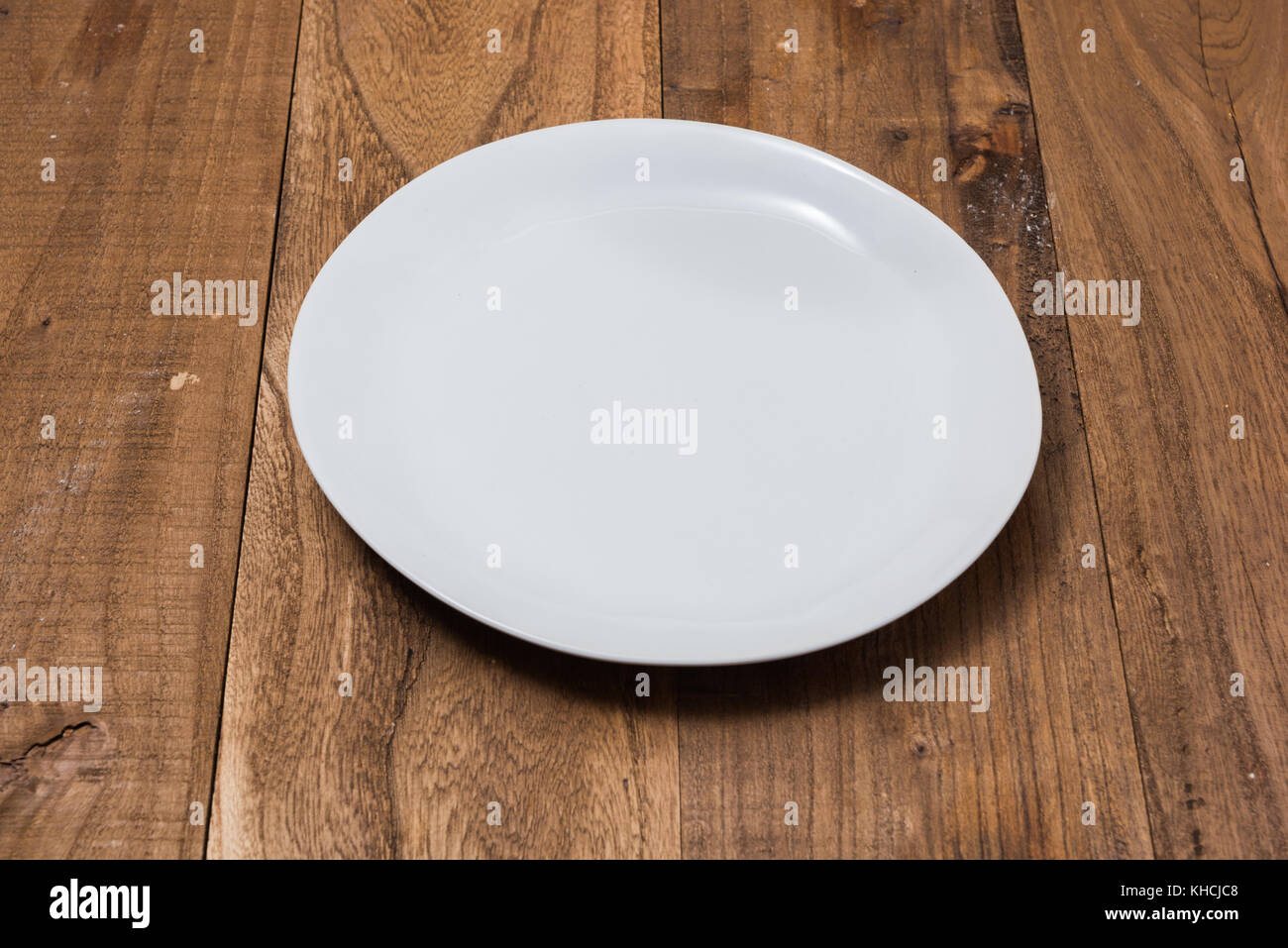 White Plate on brown wooden table background side view Stock Photo - Alamy