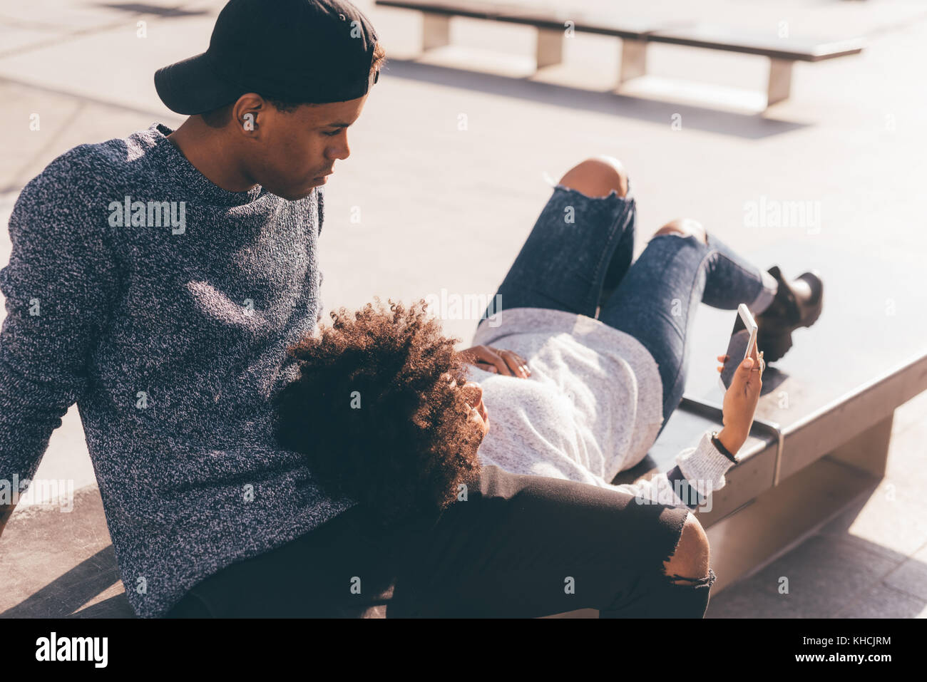 Young multiethnic couple relaxing outdoor, she is lying on his leg ...