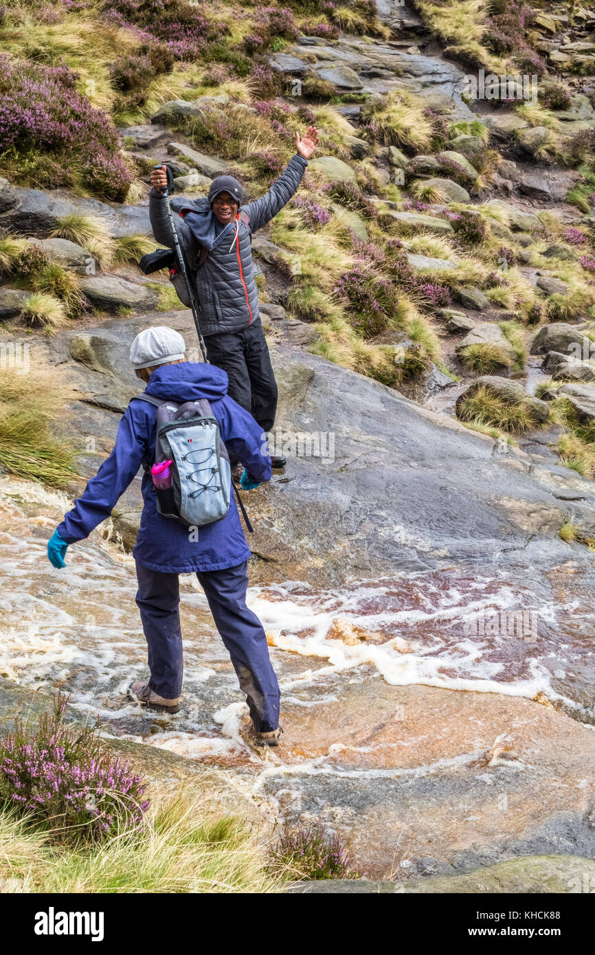 Walkers walking through fast flowing stream water while crossing ...