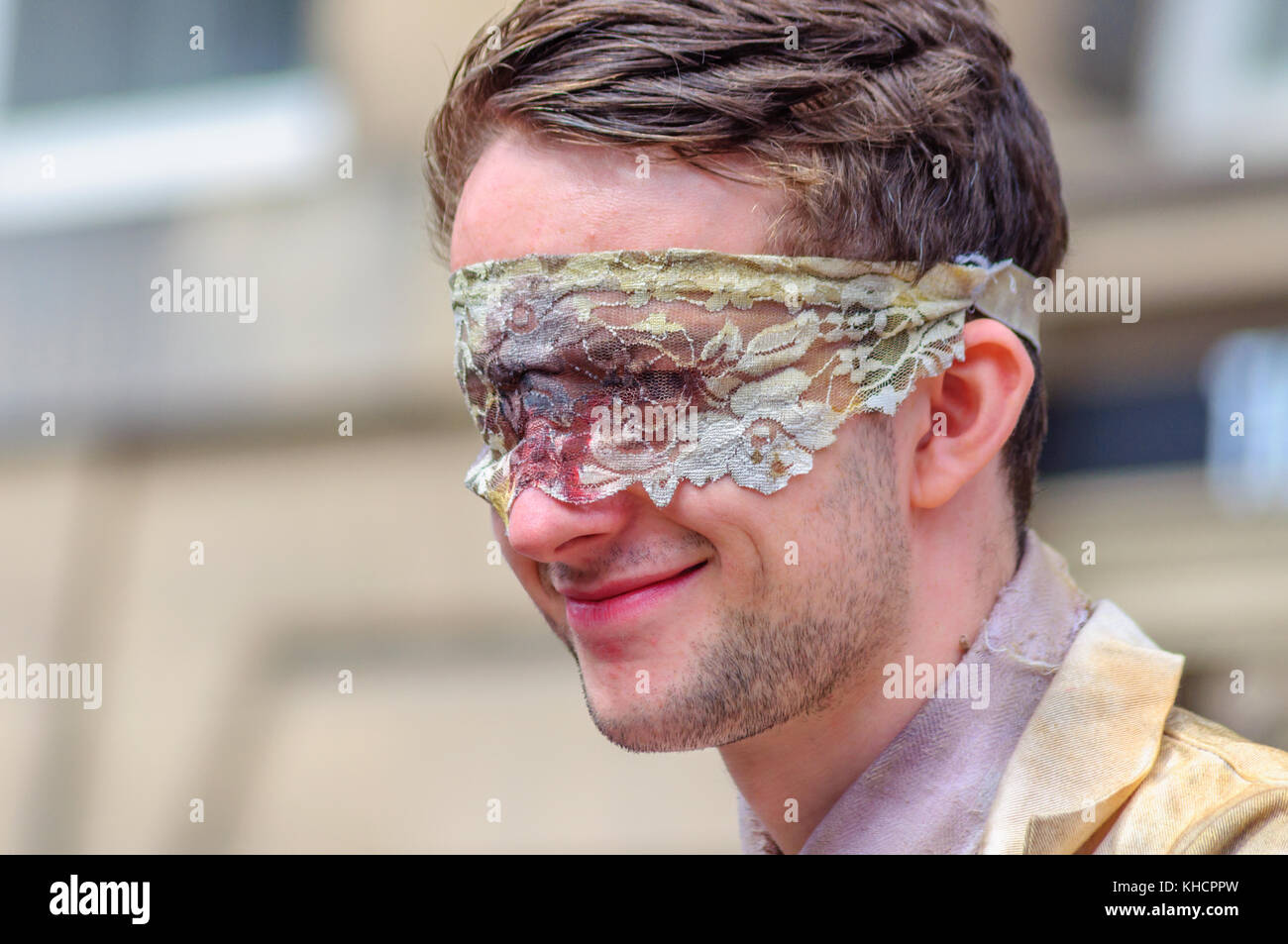 Male performer wearing a lace covering over his eyes on the Royal Mile ...