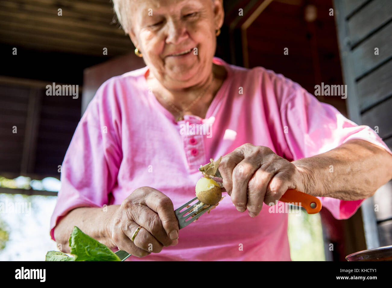 Senior woman pealing potatoes Stock Photo - Alamy