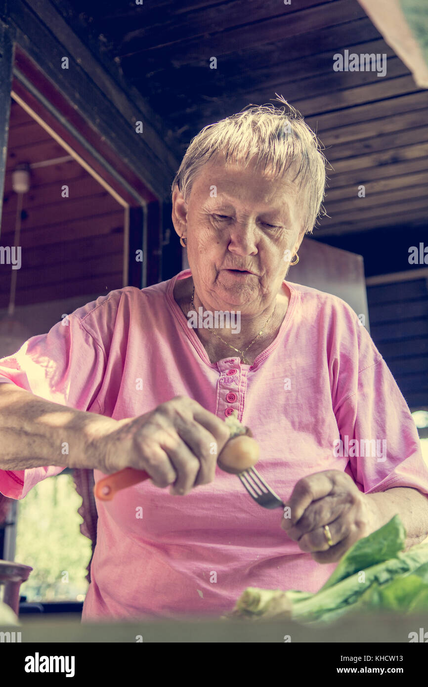 Senior woman pealing potatoes Stock Photo - Alamy